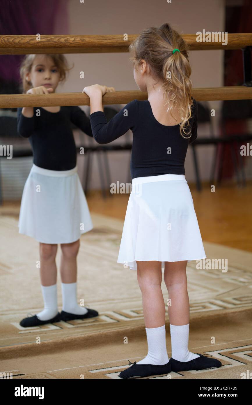 Girl at ballet barrel. Ballet pas. First position. Reflection in mirror ...