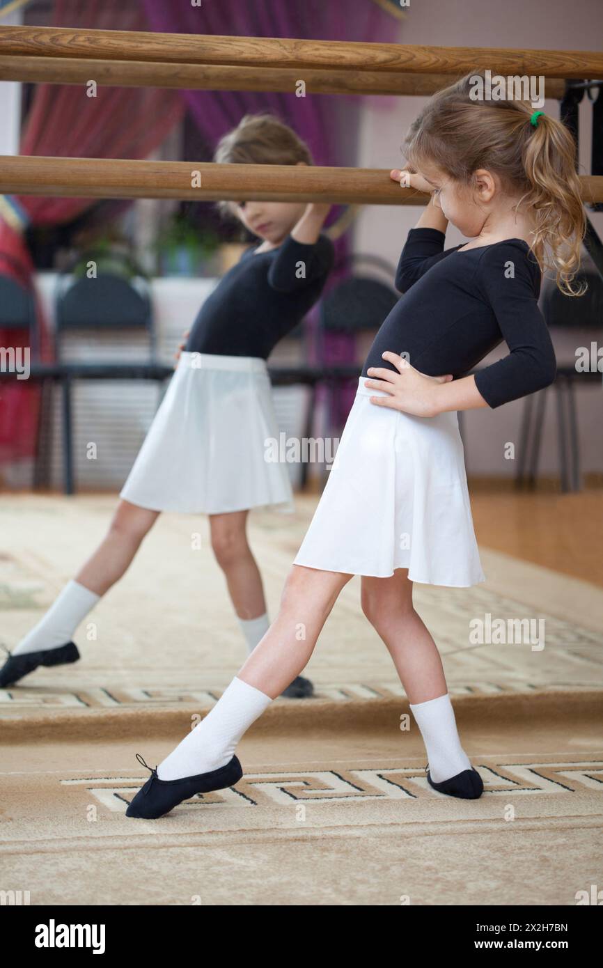 Girl at ballet barre. Ballet pas. Left profile. Reflection in mirror ...