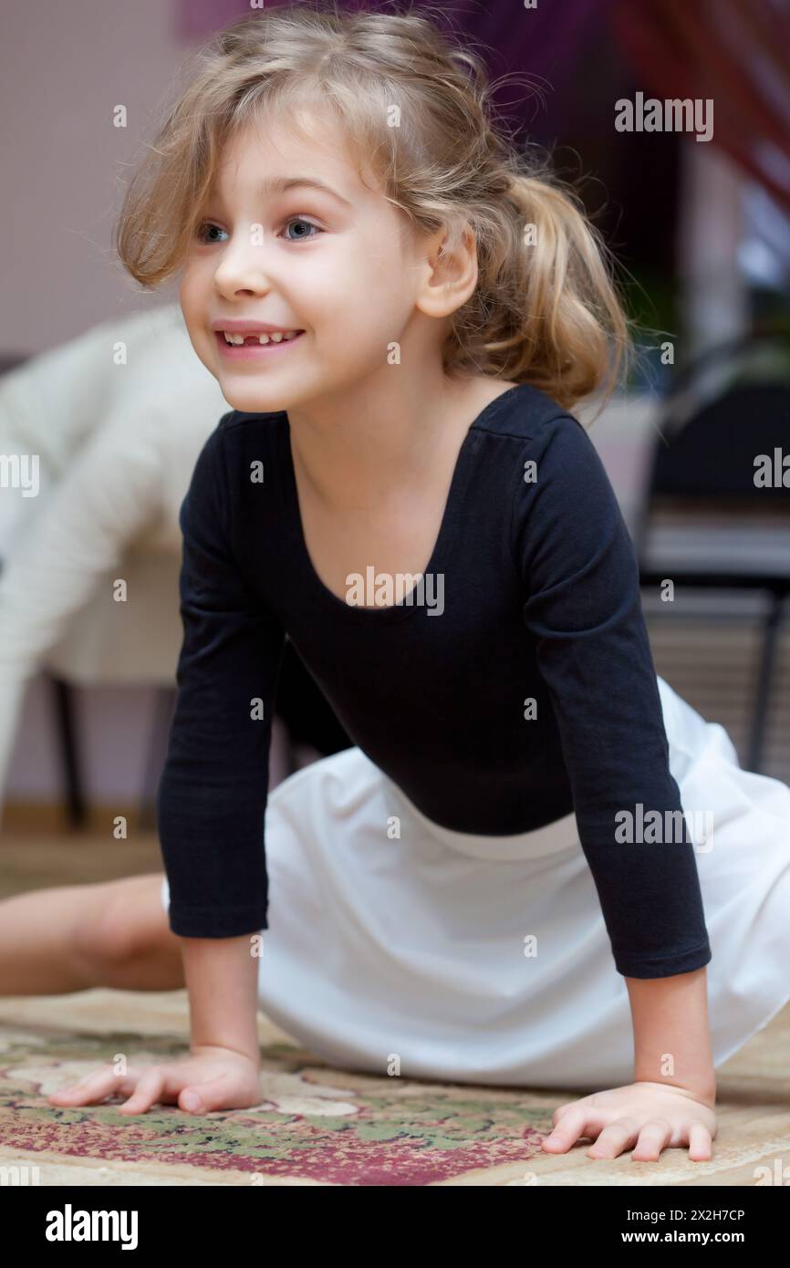 Little girl carries out exercise - cross-section splits. Gap-toothed ...