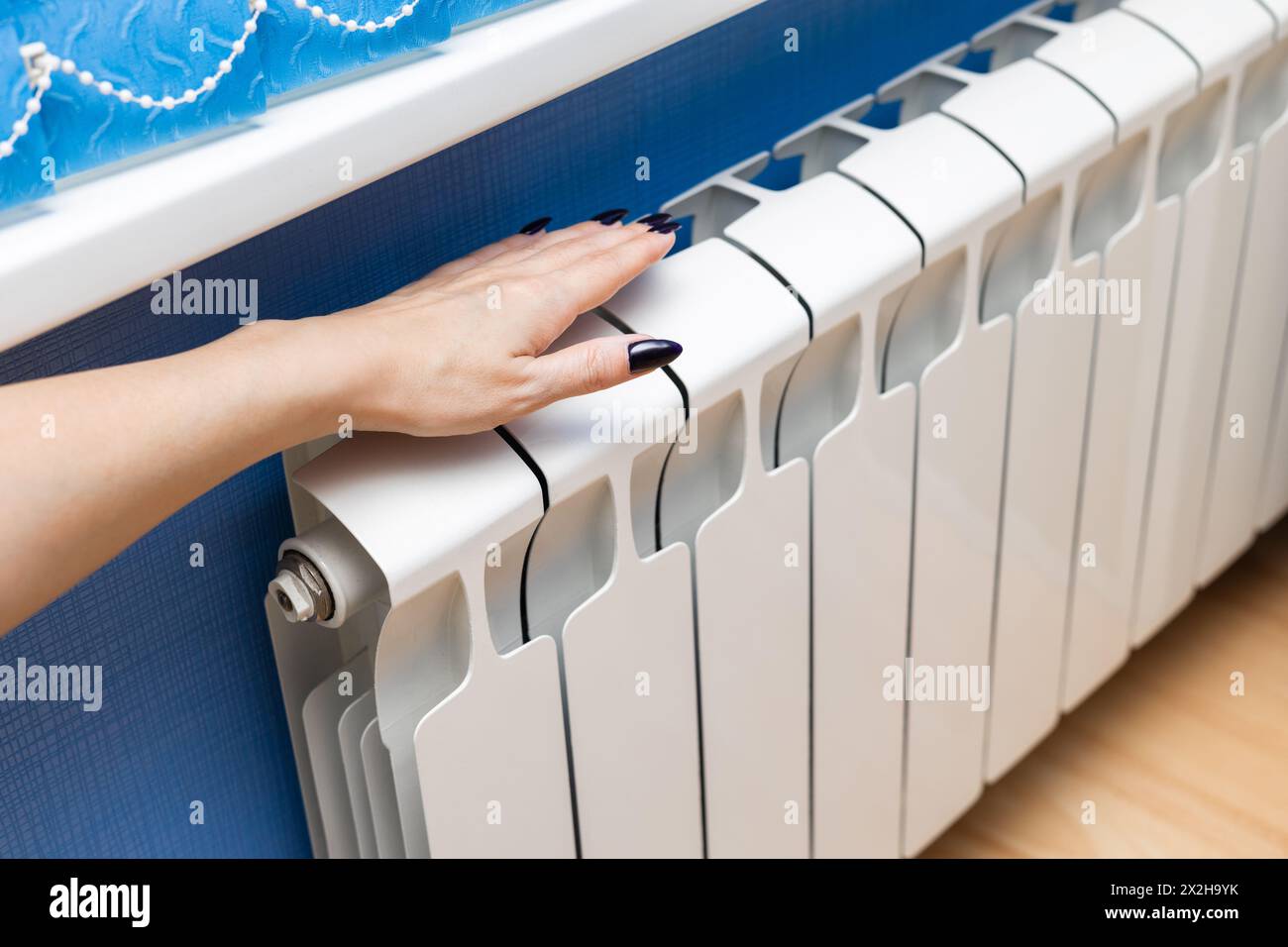 man checking the temperature of a heating radiator. a woman holds her ...