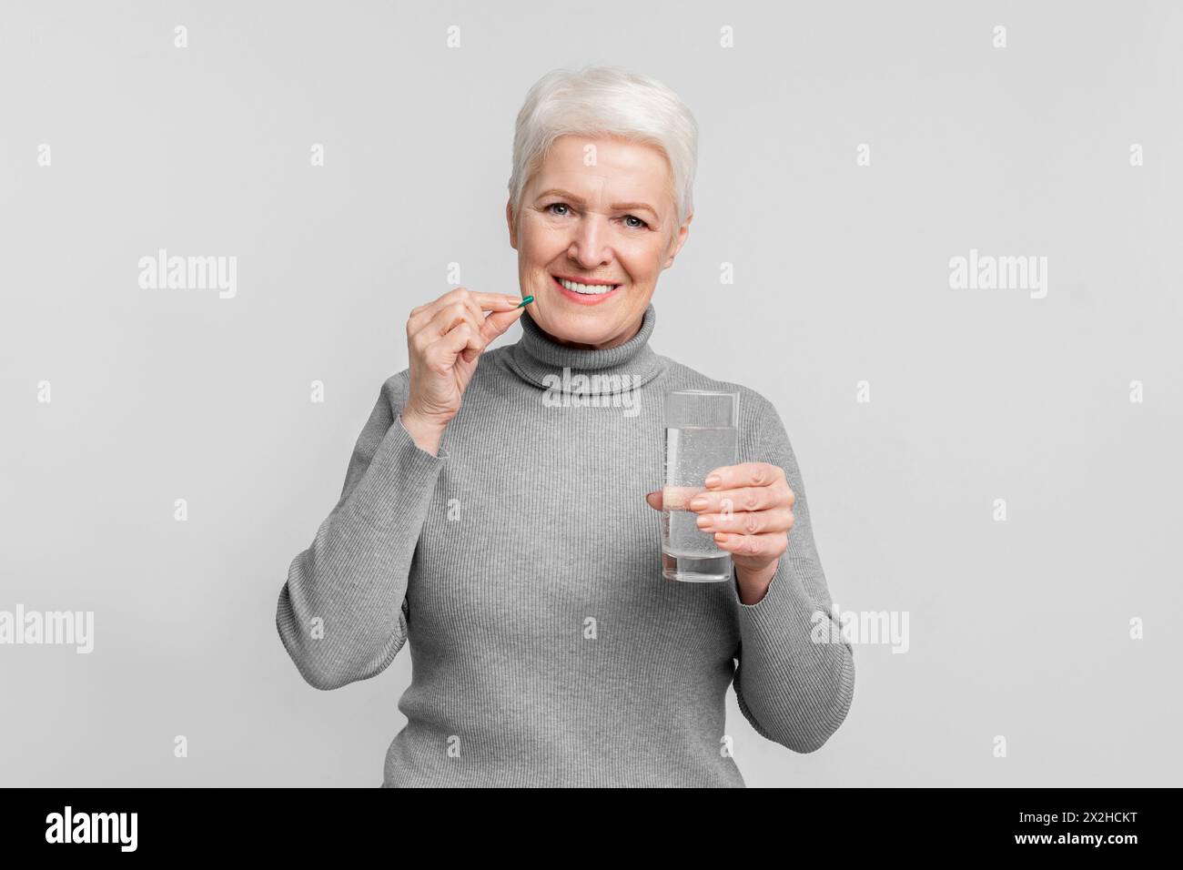 Senior lady holding pill and water glass Stock Photo - Alamy