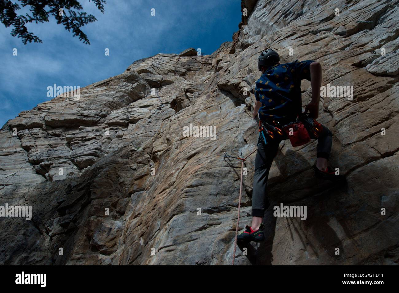 Back of male climber on rock face showing foot position and reaching ...