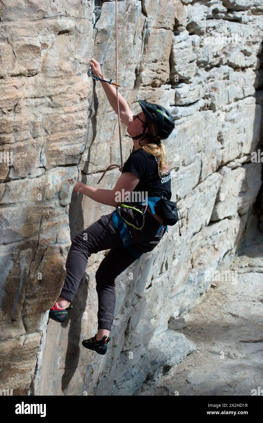 Male climber on rock face showing foot position and reaching for hand ...