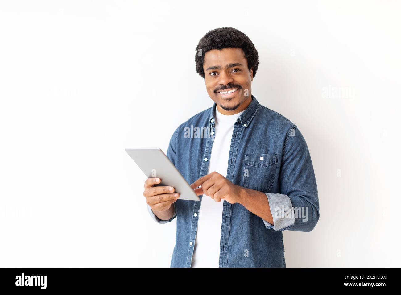 Guy using a tablet with a smile on his face Stock Photo - Alamy