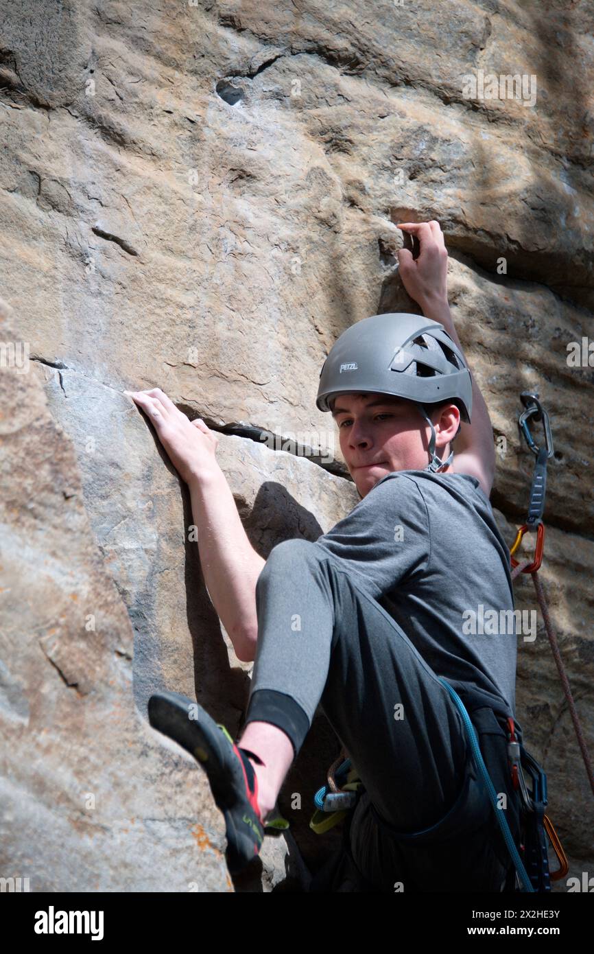 Male climber looking at foot for position on climbing rock face Stock ...