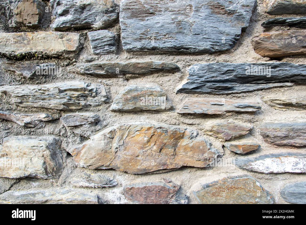 Gray structural stone wall of the ancient building consists of old dark ...