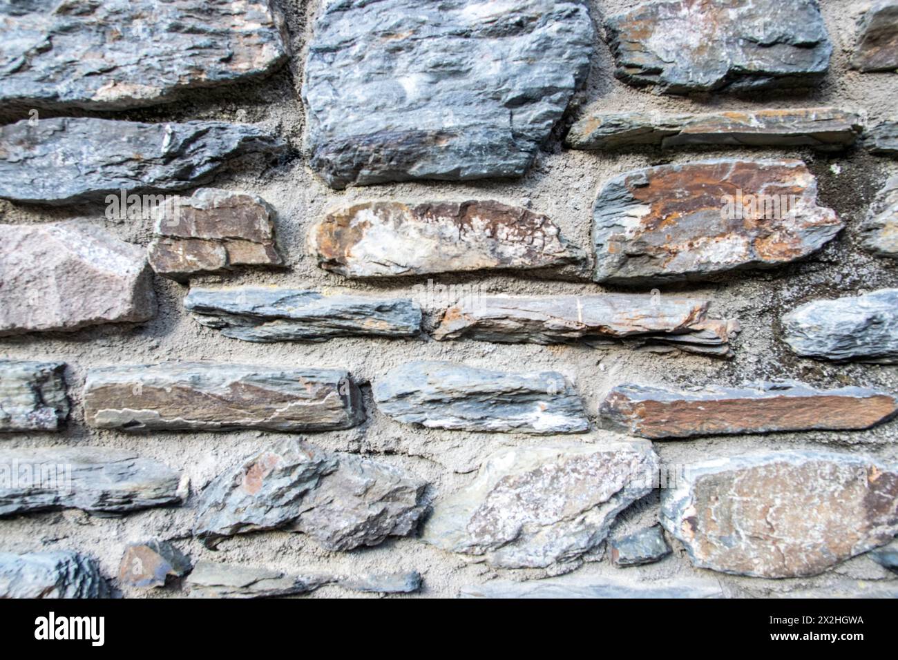 Gray structural stone wall of the ancient building consists of old dark ...