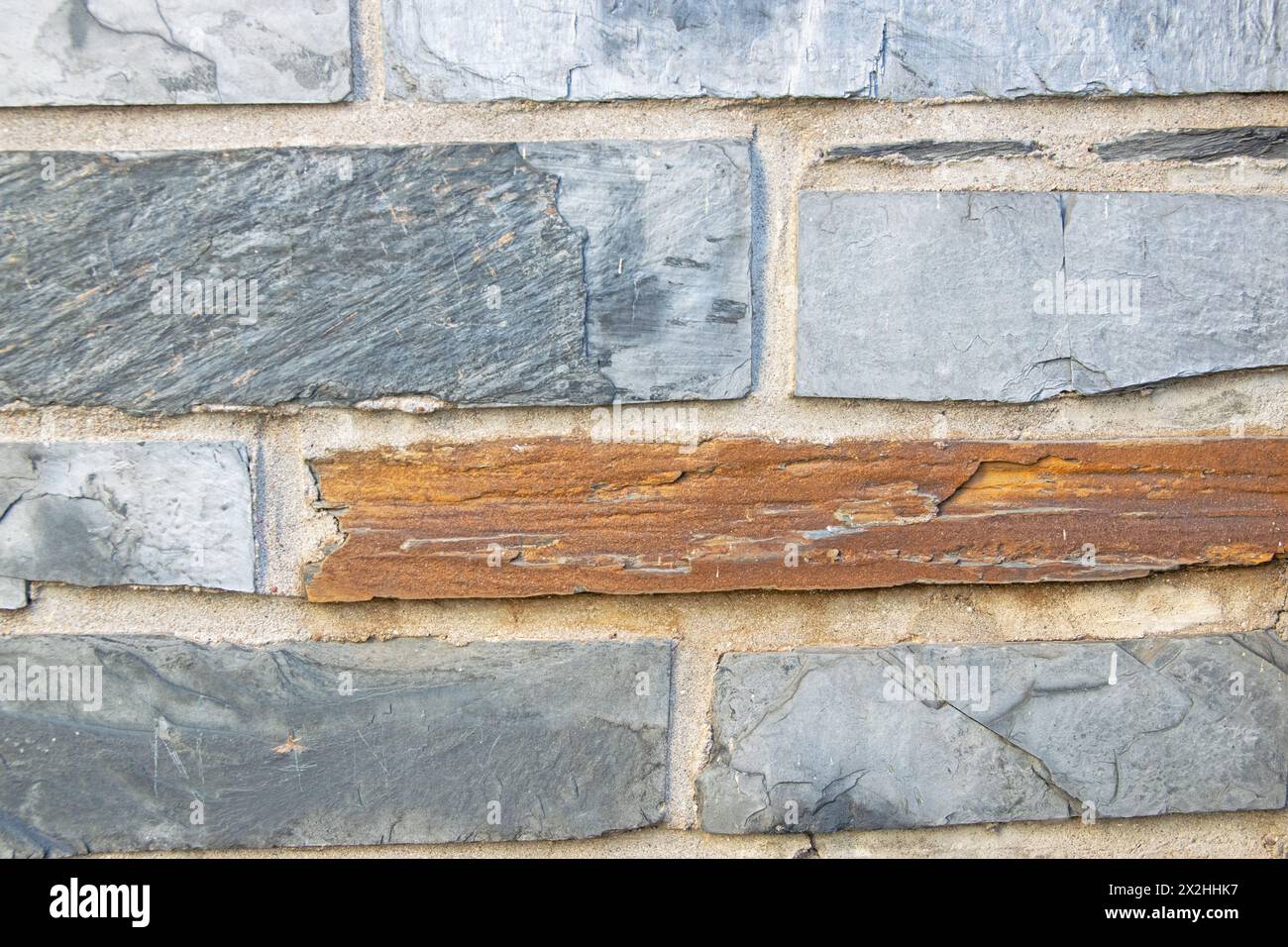 Gray structural stone wall of the ancient building consists of old dark ...