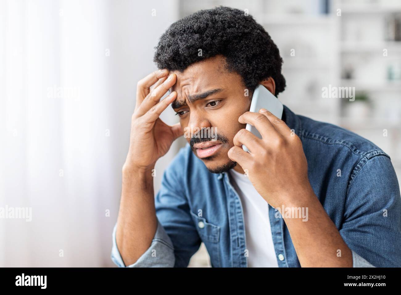 Worried man talking on the phone at home Stock Photo - Alamy