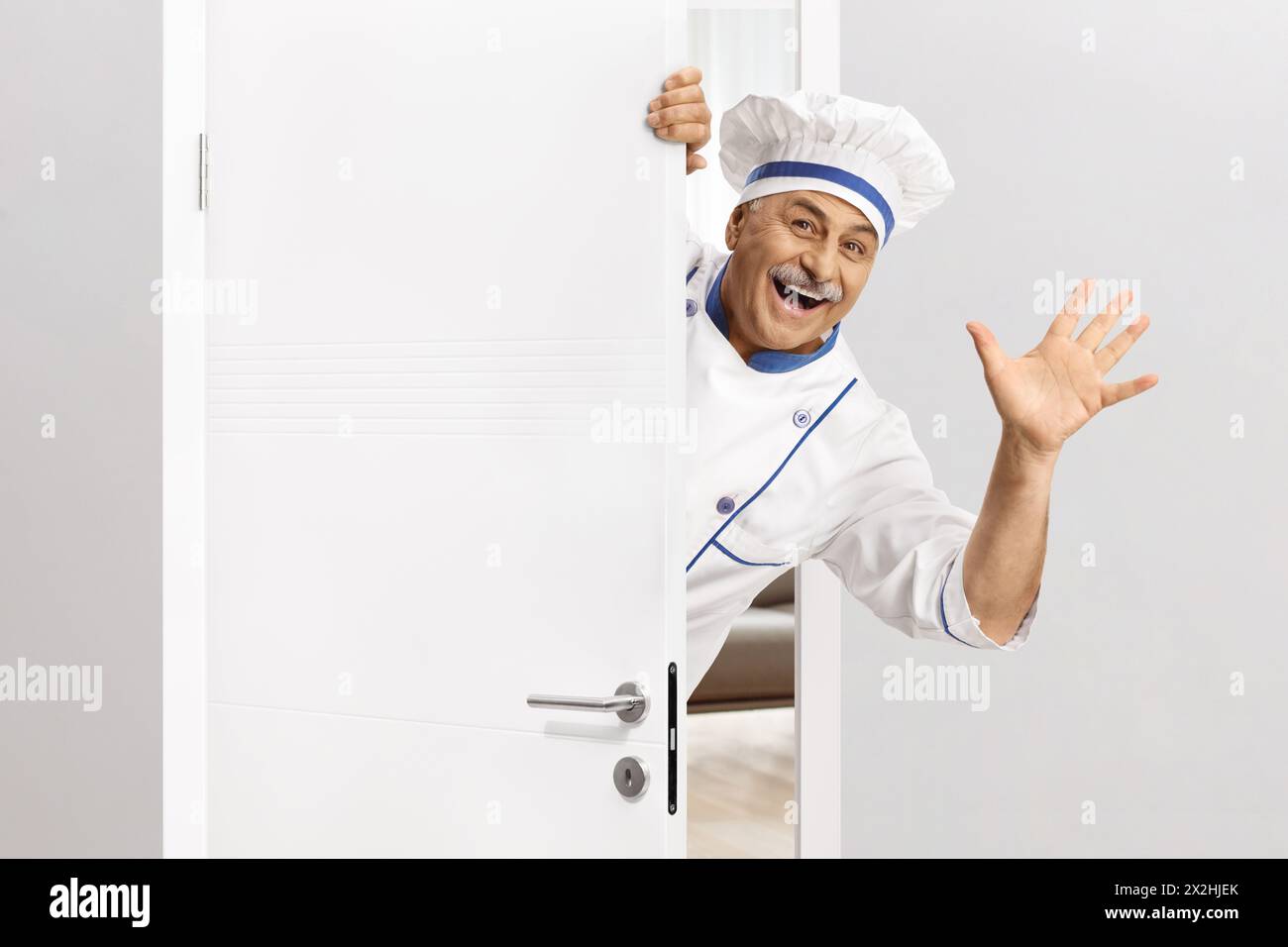 Mature chef in a uniform opening a door and waving Stock Photo - Alamy