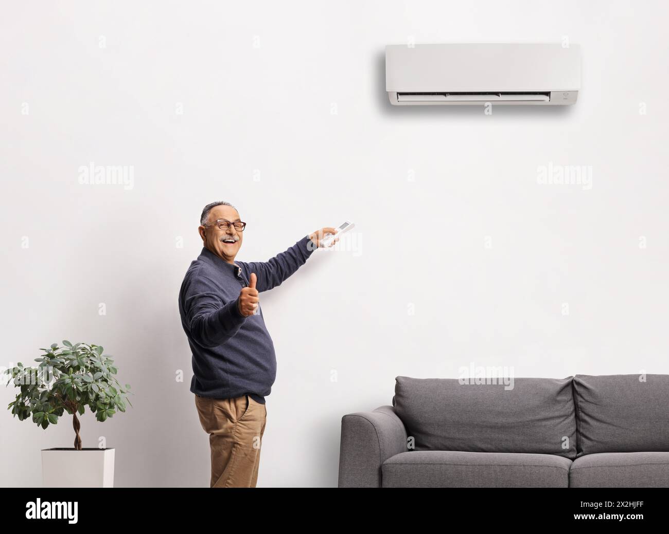 Mature man putting on an air conditioning unit at home and gesturing ...