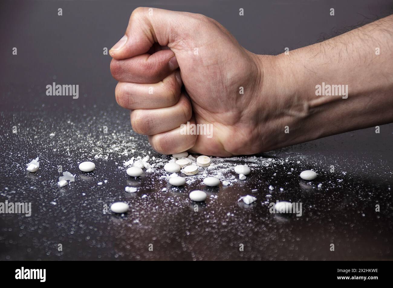 Stop drug addiction concept. Young hand crushing white pills with fist ...
