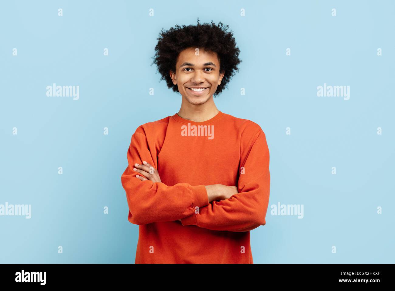 Confident guy crossing arms and smiling on blue background Stock Photo ...