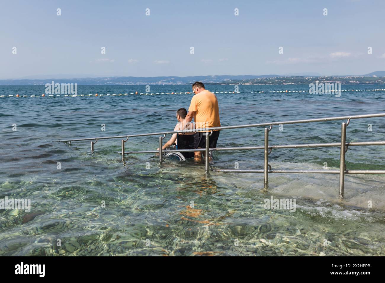 Wheelchair user entering the sea with the help of an assistant on ...