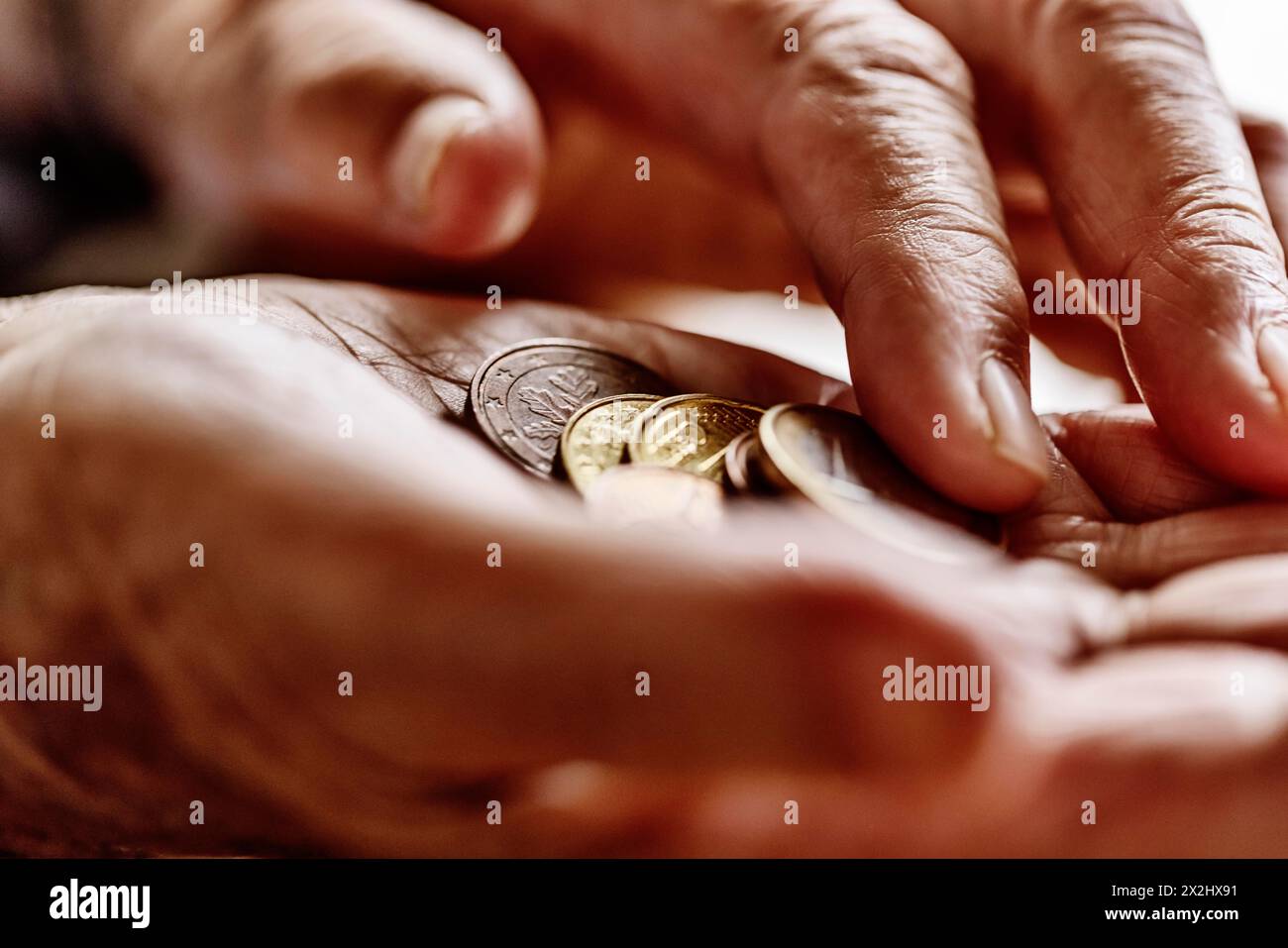 Coin money in the wrinkled hand of a senior citizen, symbolising ...