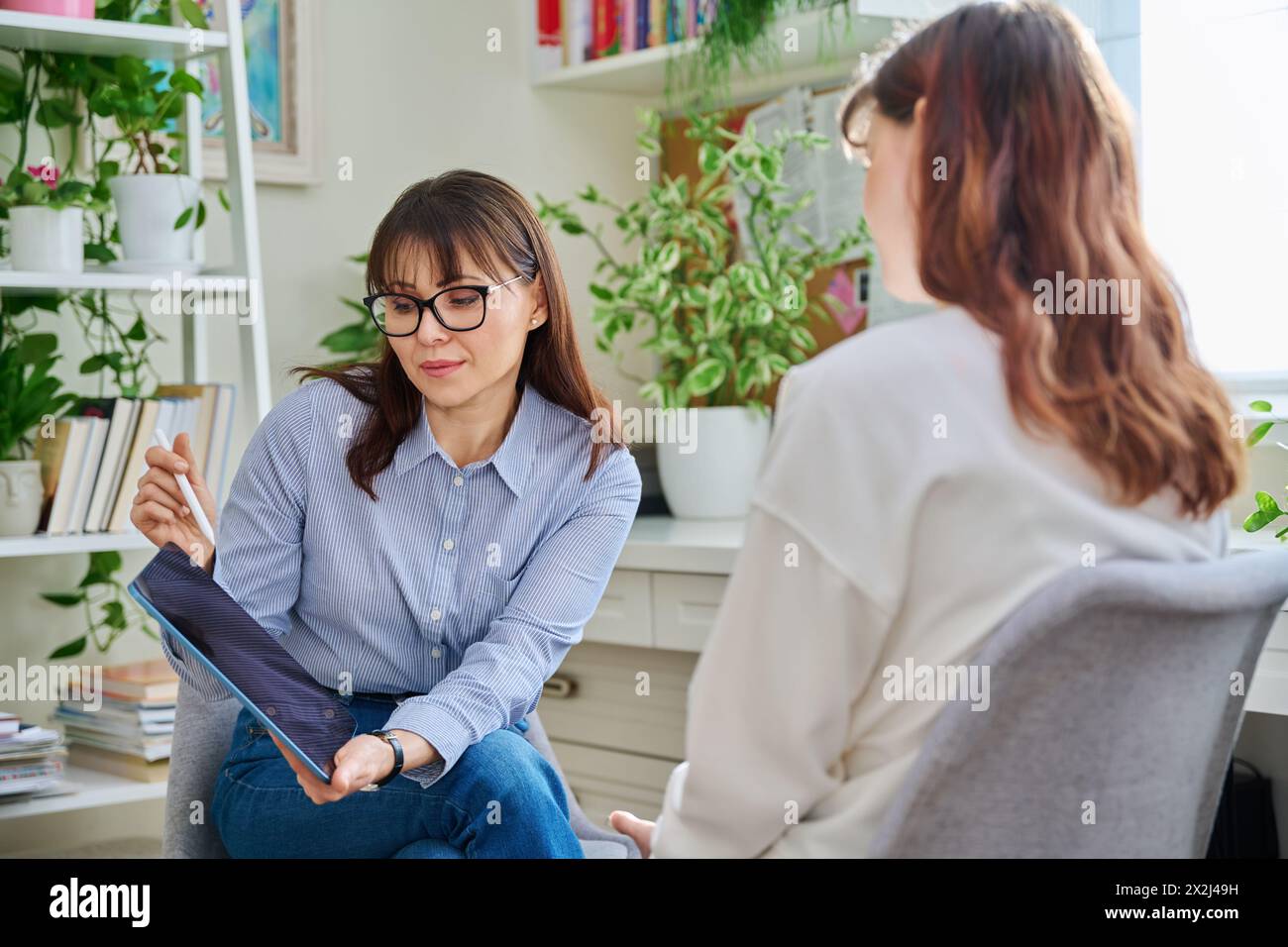 Professional mental therapist working with young woman, sitting ...