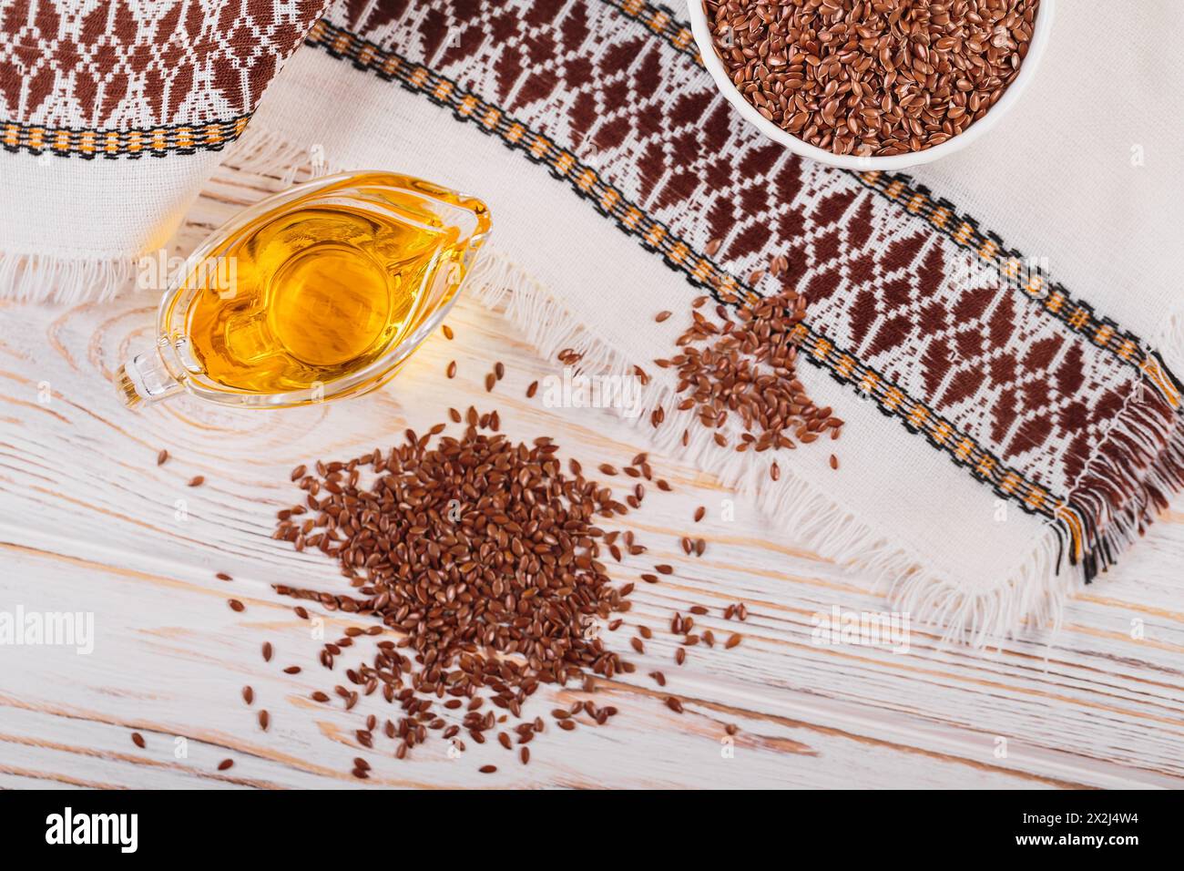 Brown linen seeds, flaxseed vegetable oil on white wooden background ...