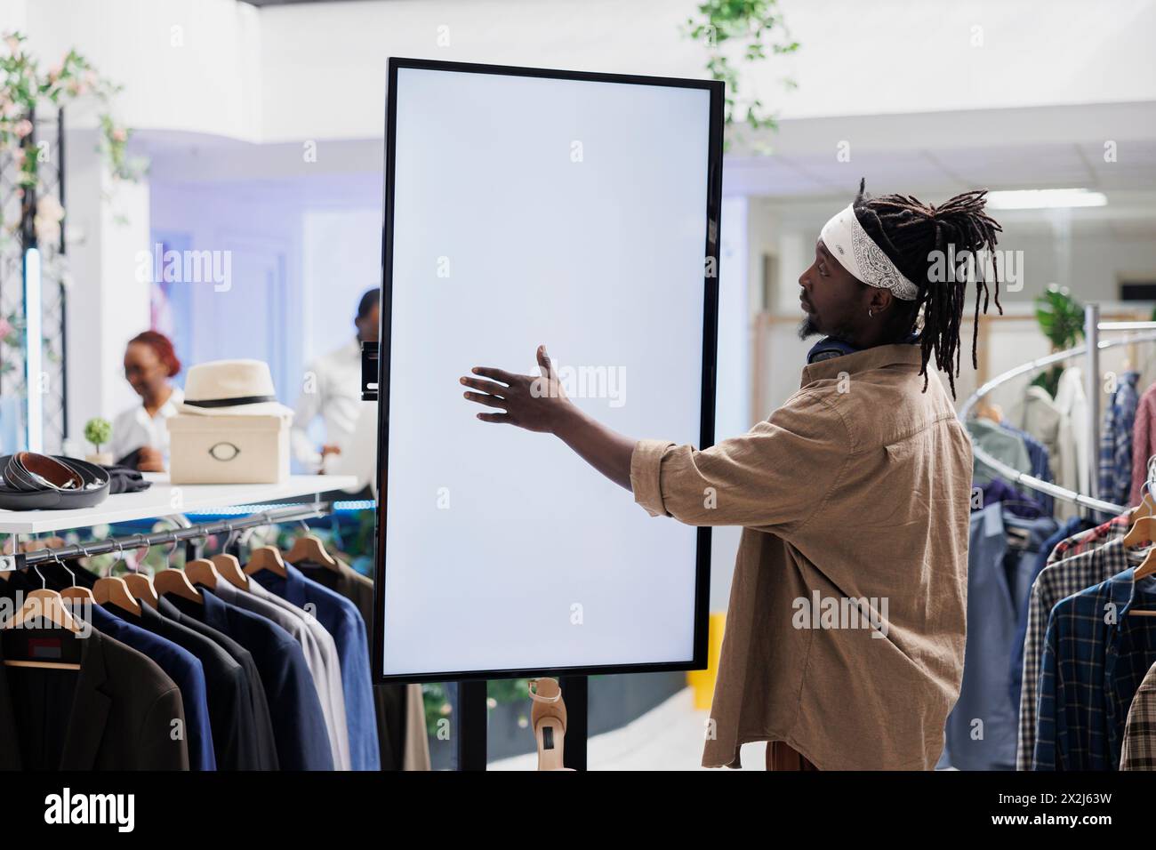 Customer using empty white smart screen to browse clothes in store ...