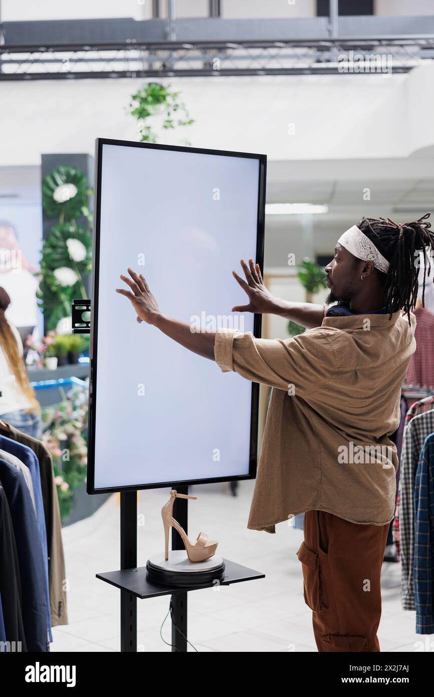 African american man interacting with digital screen offering shoes to ...