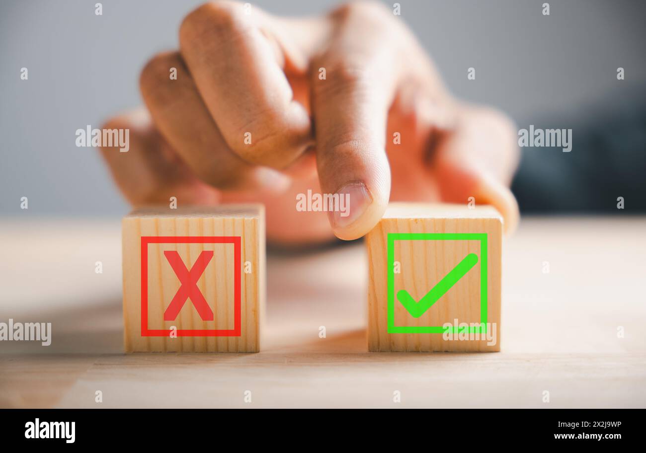 Between two wooden cubes businessman finger indicates check marks for ...