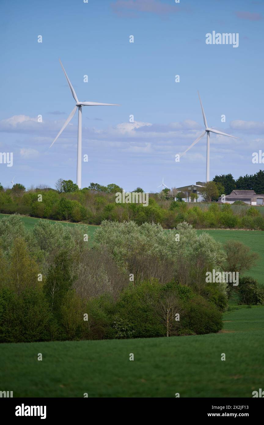 Two wind turbines over English countryside against blue sky with small ...