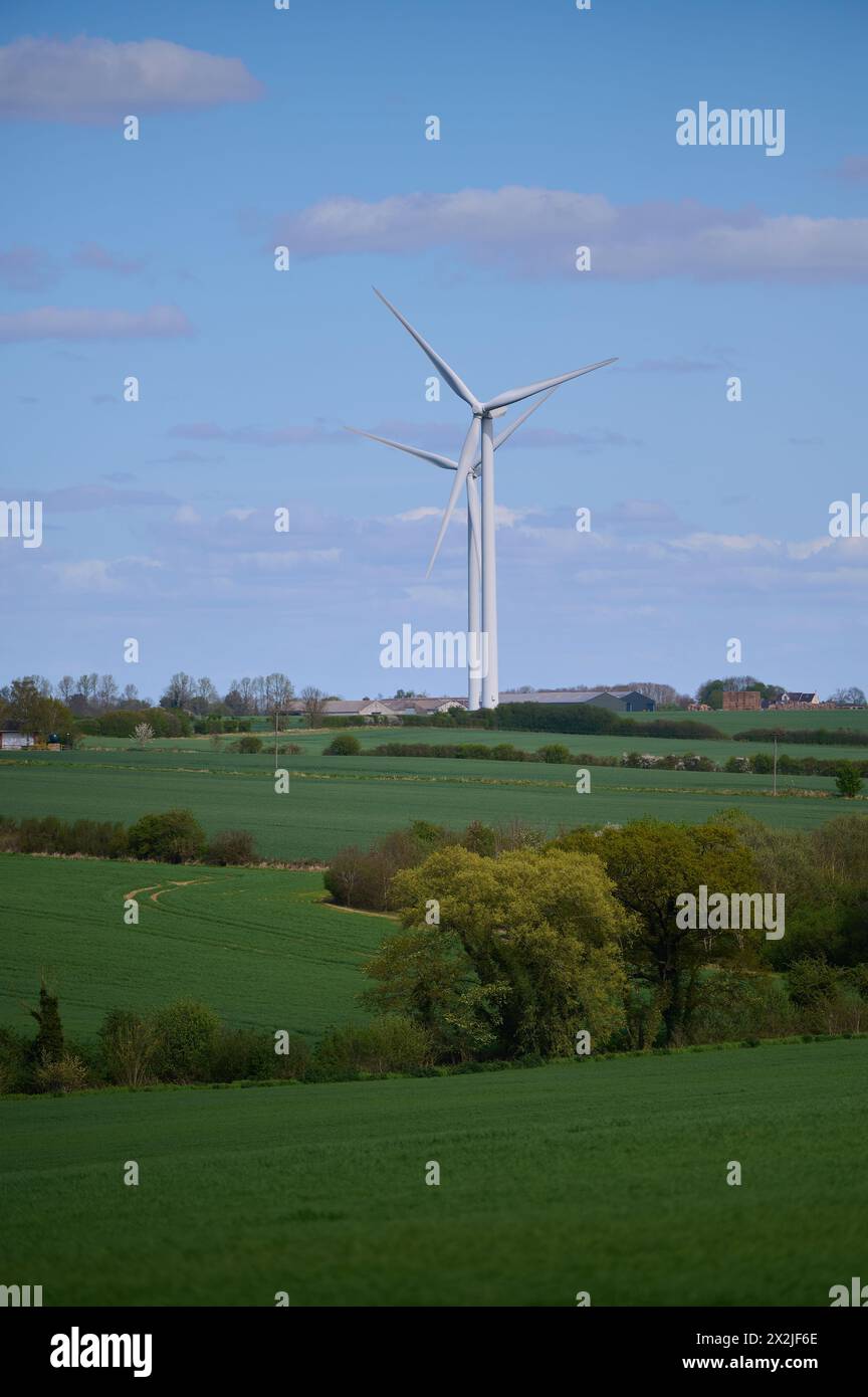 Two wind turbines over English countryside against blue sky with small ...
