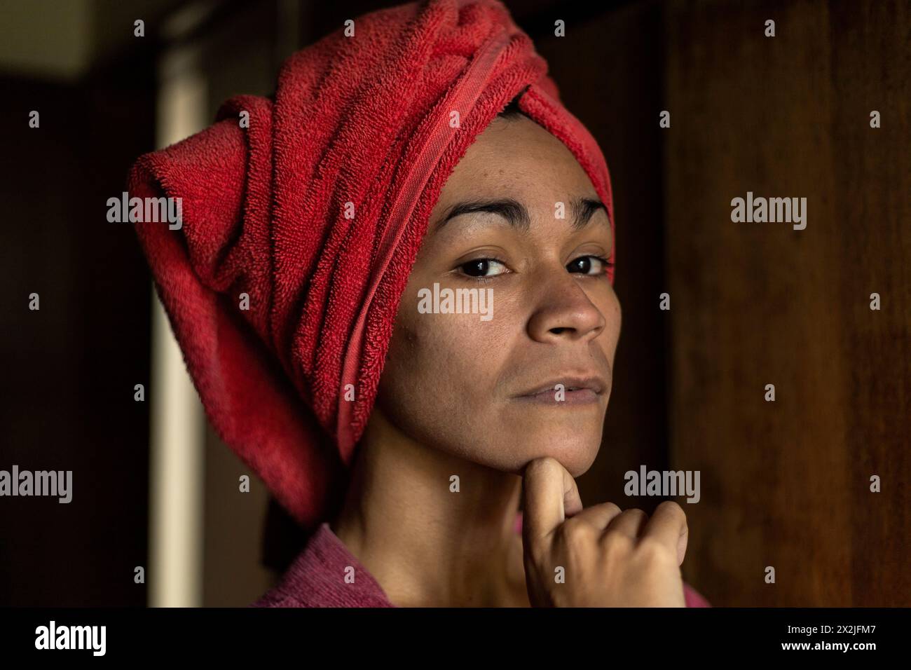 Young transgender man (26) with bathrobe and towel covering his head ...