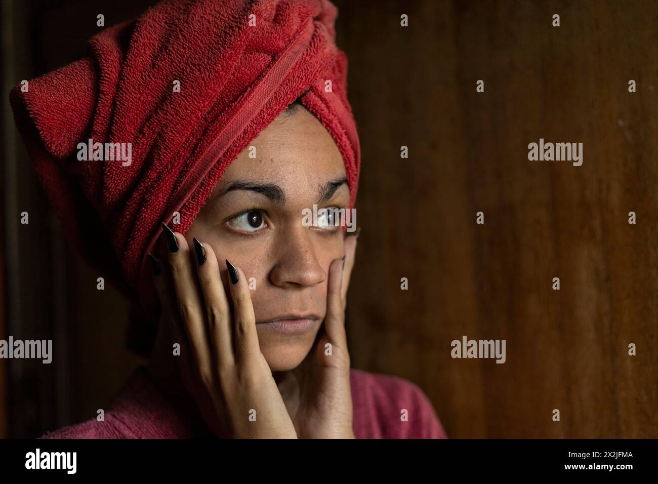 Young transgender man (26) with bathrobe and towel covering his head ...