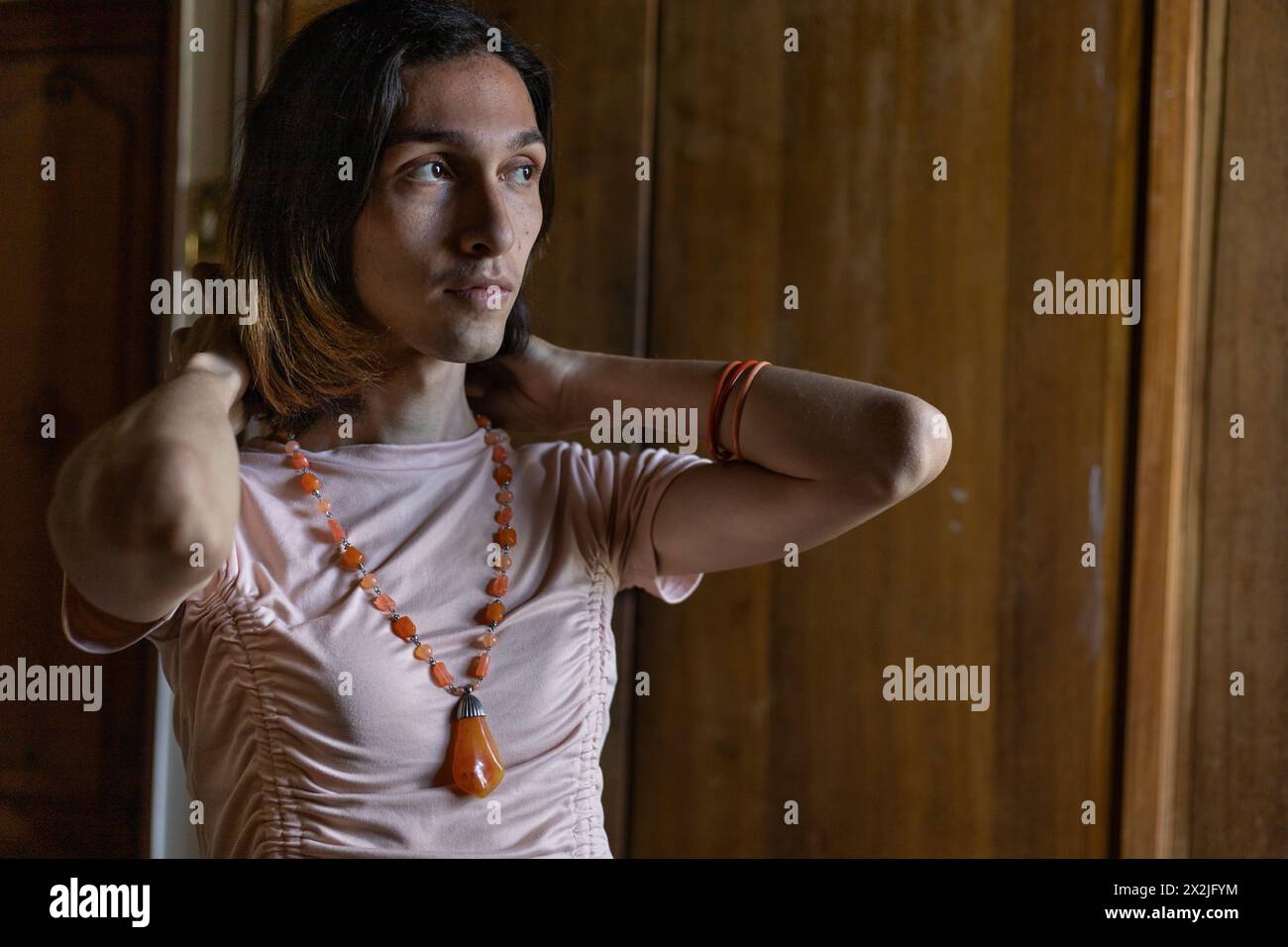 Young transgender man (22) is in his room putting on his accessories ...