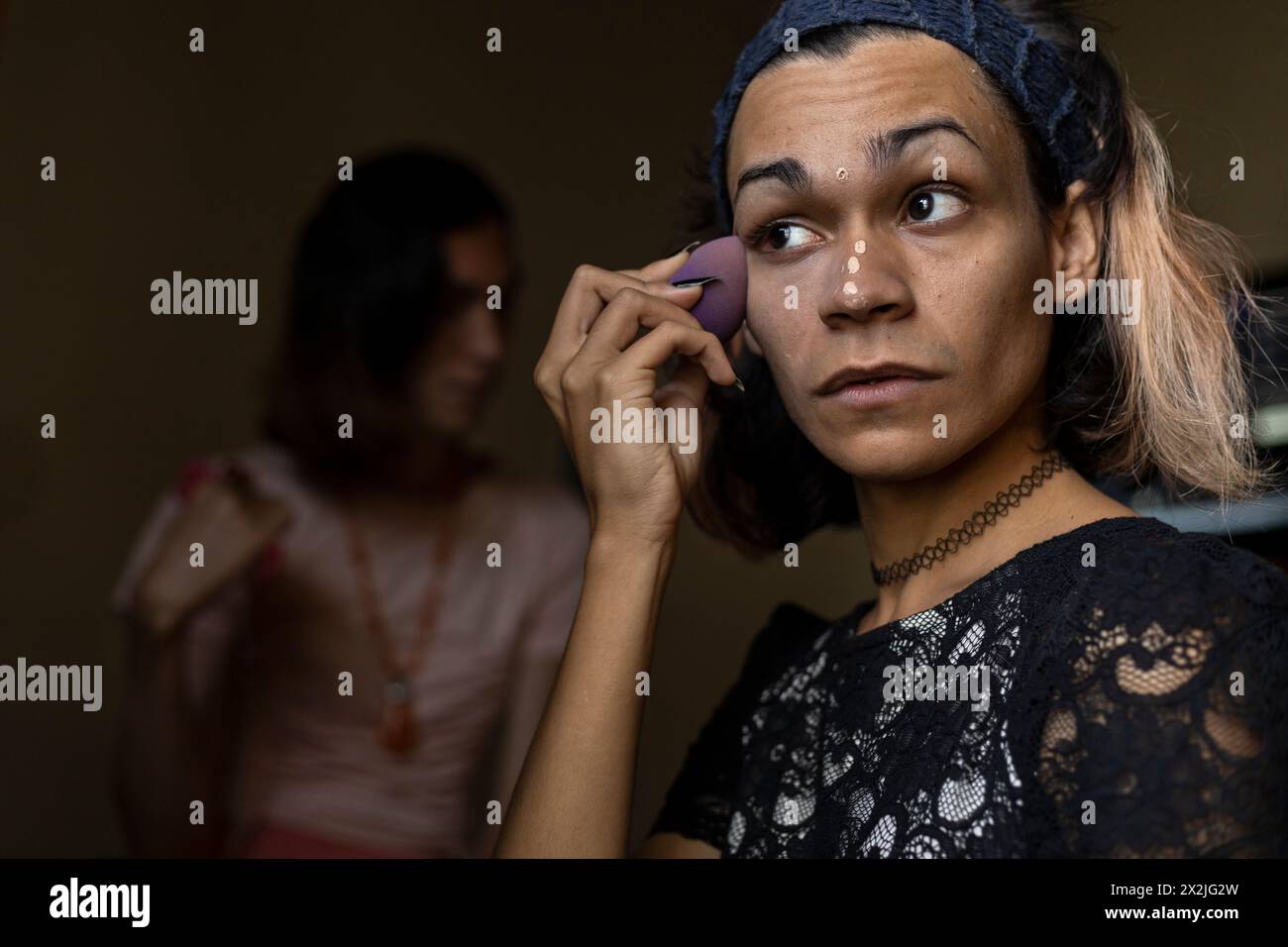 Young transgender man (26) is in his room applying makeup. Transgender ...