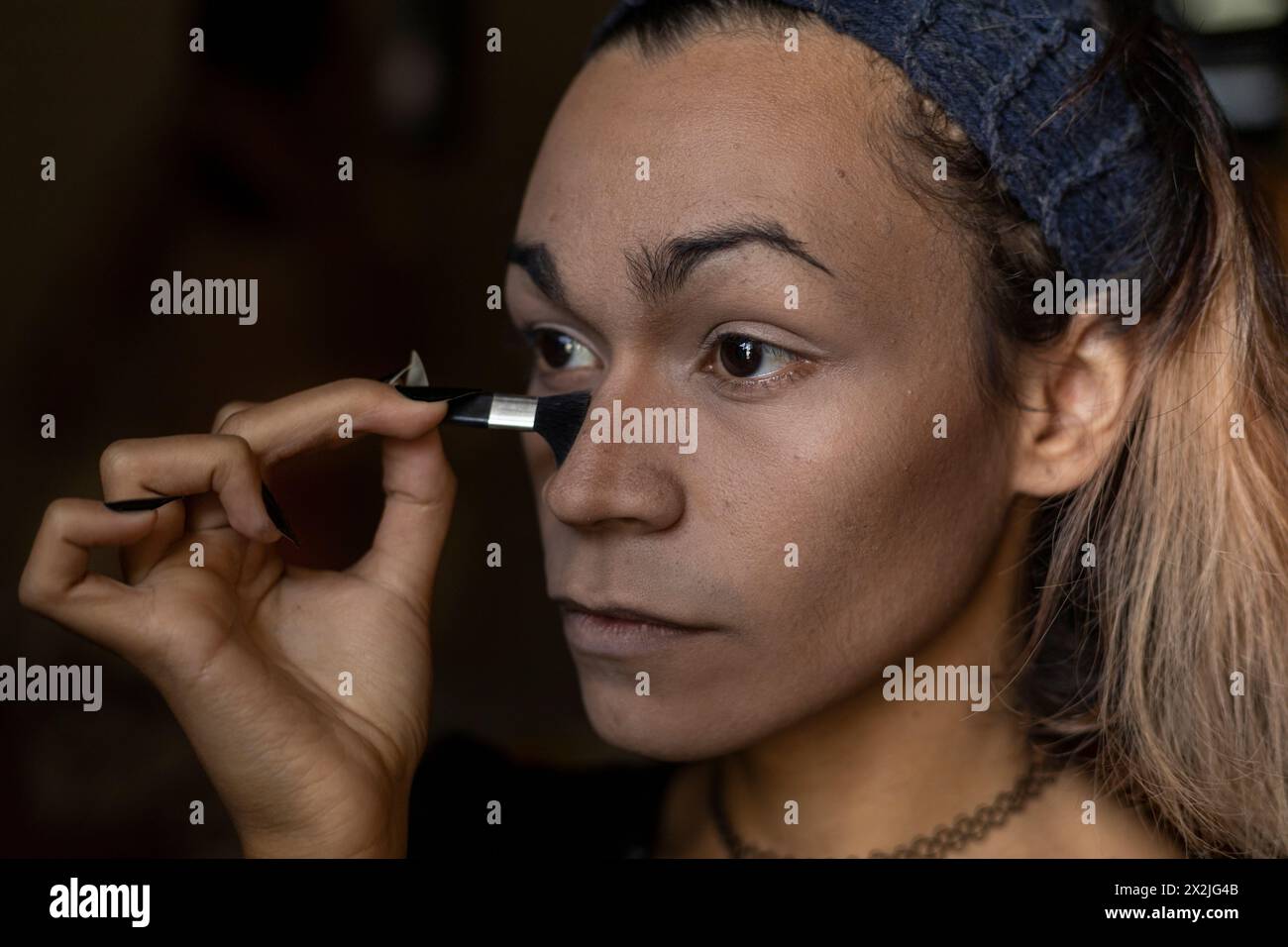 Young transgender man (26) is in his room applying makeup. Transgender ...