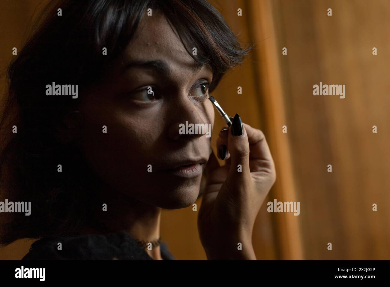 Young transgender man (26) is in his room applying makeup. Transgender ...