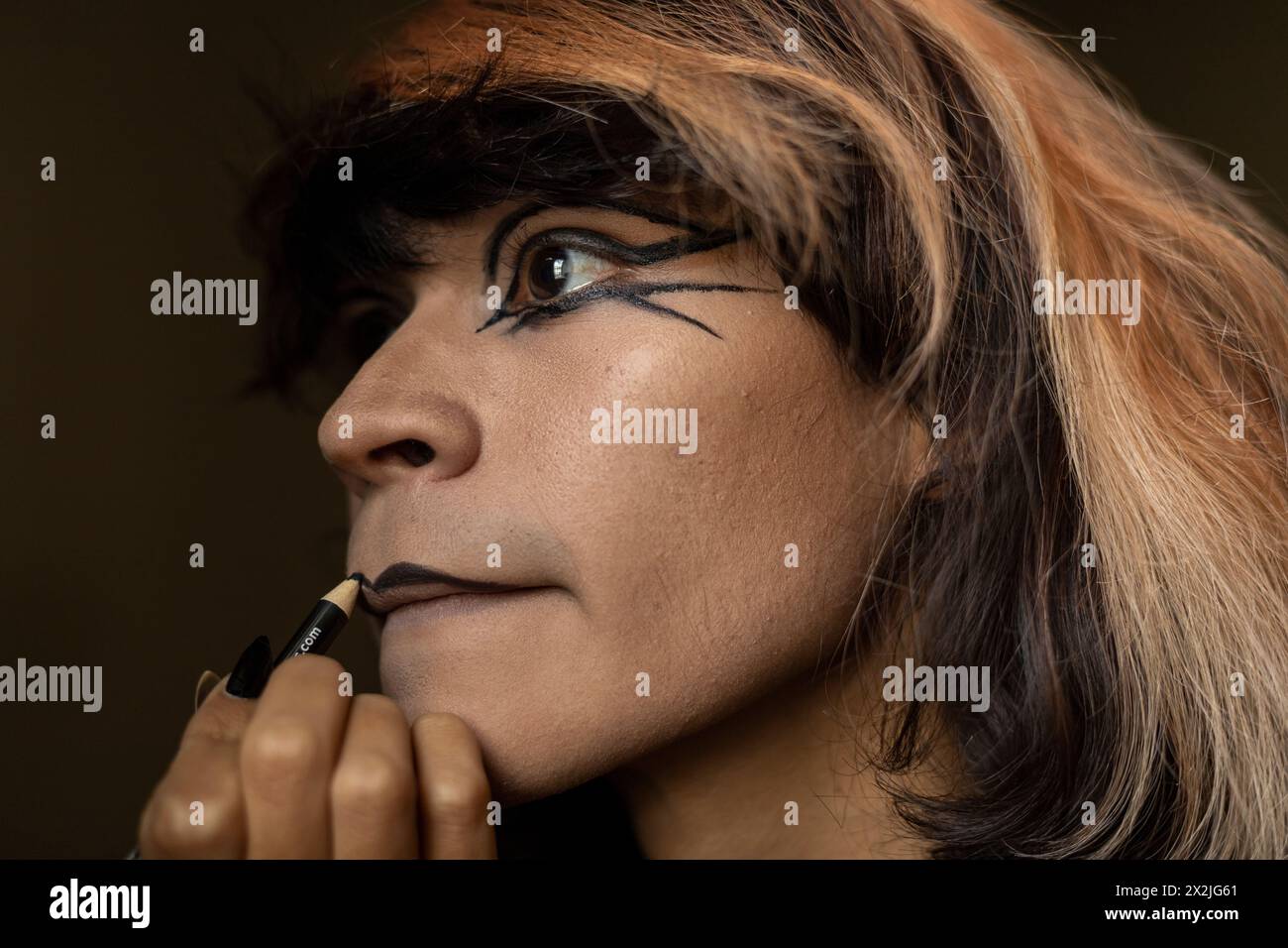 Young transgender man (26) is in his room applying makeup. Transgender ...