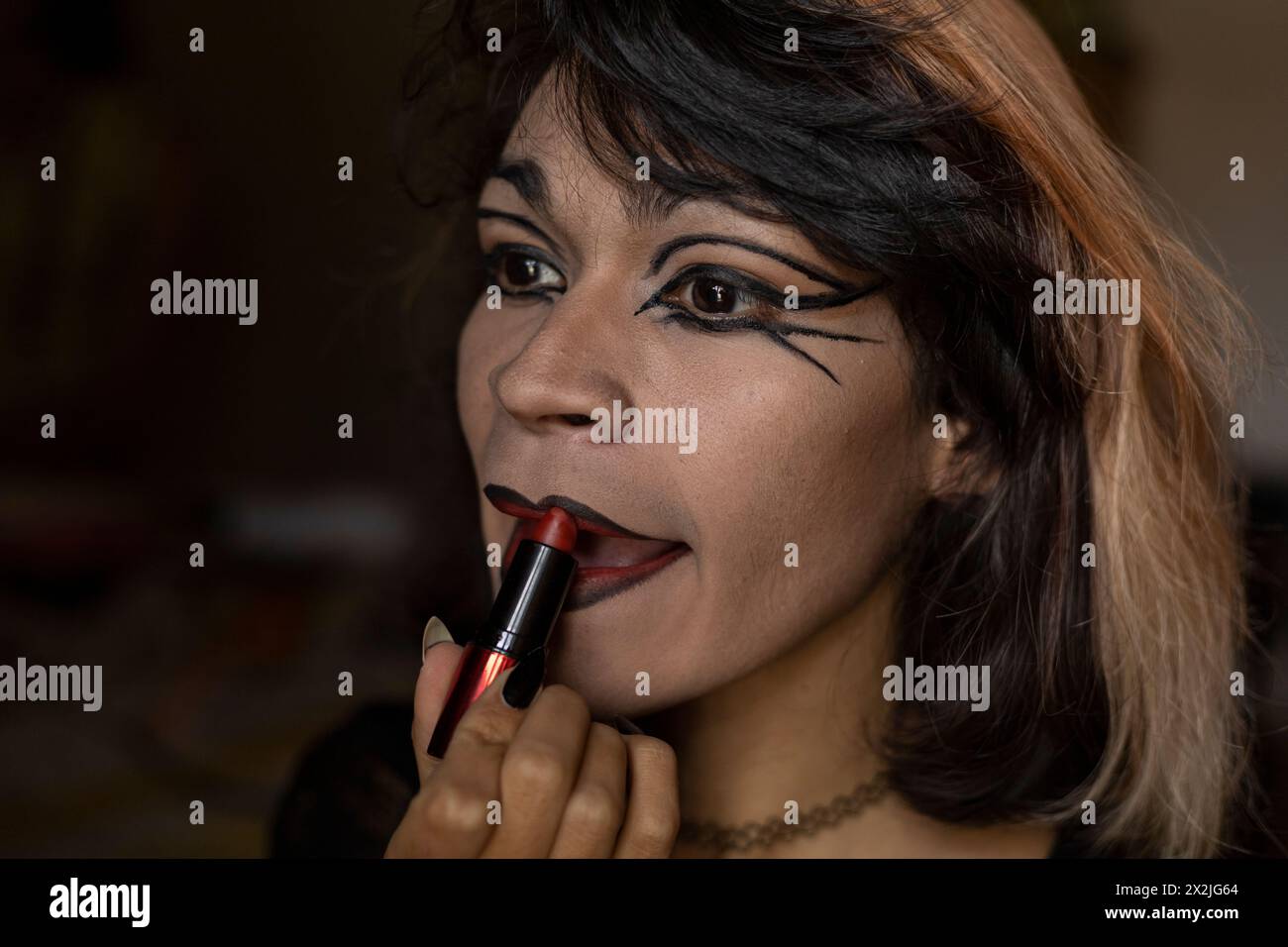 Young transgender man (26) is in his room applying makeup. Transgender ...