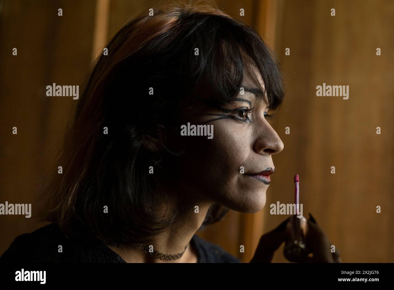 Young transgender man (26) is in his room applying makeup. Transgender ...