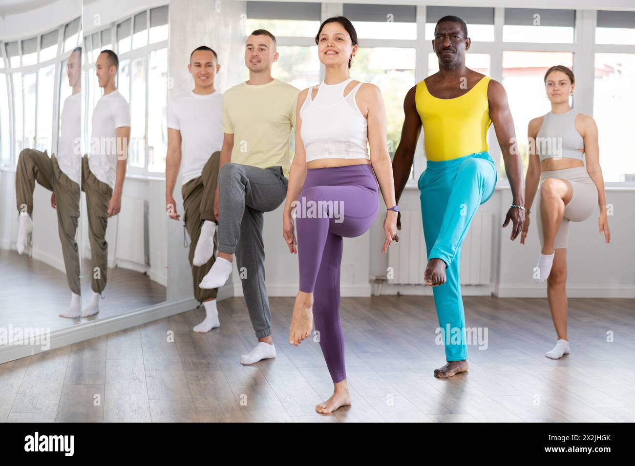 Multinational group of young people stand in row holding hands ...