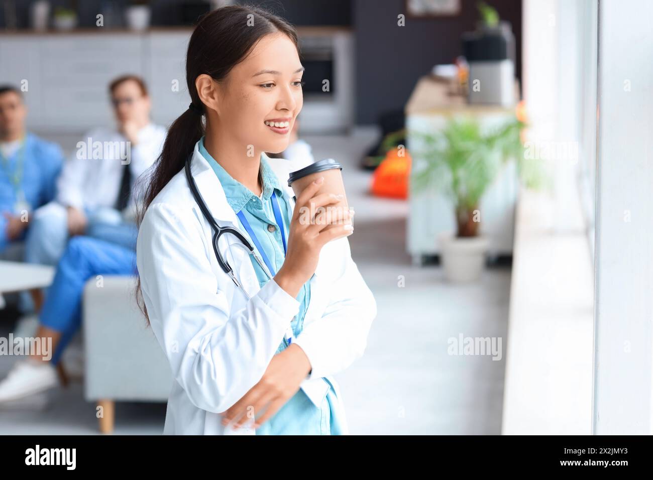 Female Asian doctor with coffee cup in hospital rest room Stock Photo ...