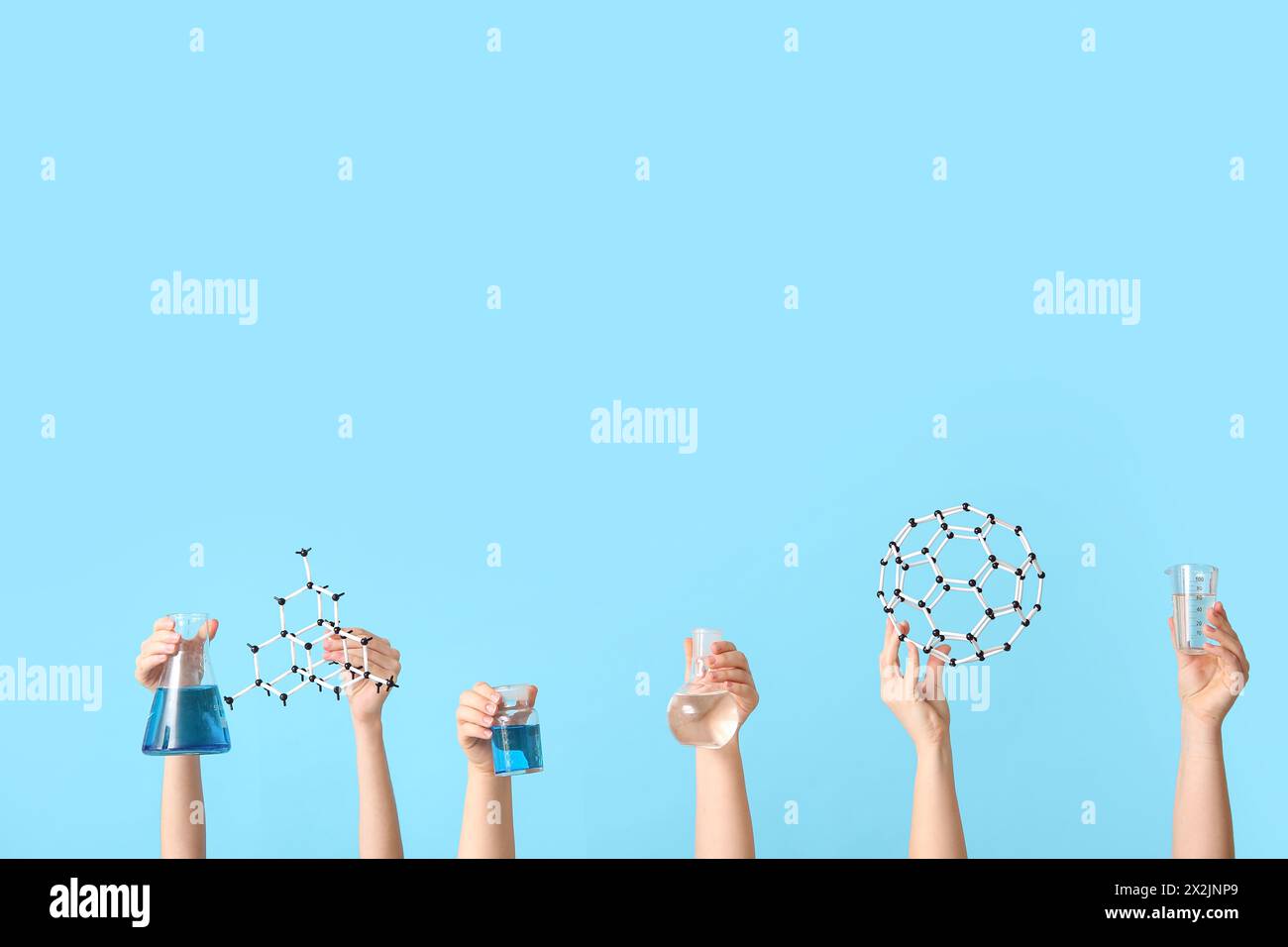 Female hands holding molecular models and filled flasks with measuring ...