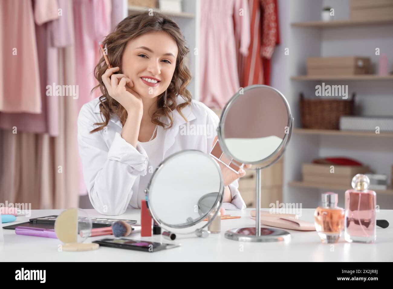 Beautiful young happy woman doing makeup for prom night in wardrobe ...