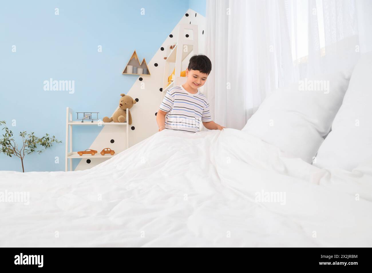 Cute happy little boy making bed in bedroom Stock Photo - Alamy