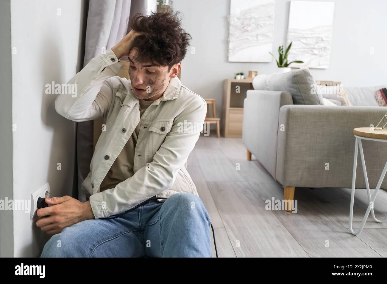 Electrocuted young man with burn face plugging into socket at home ...