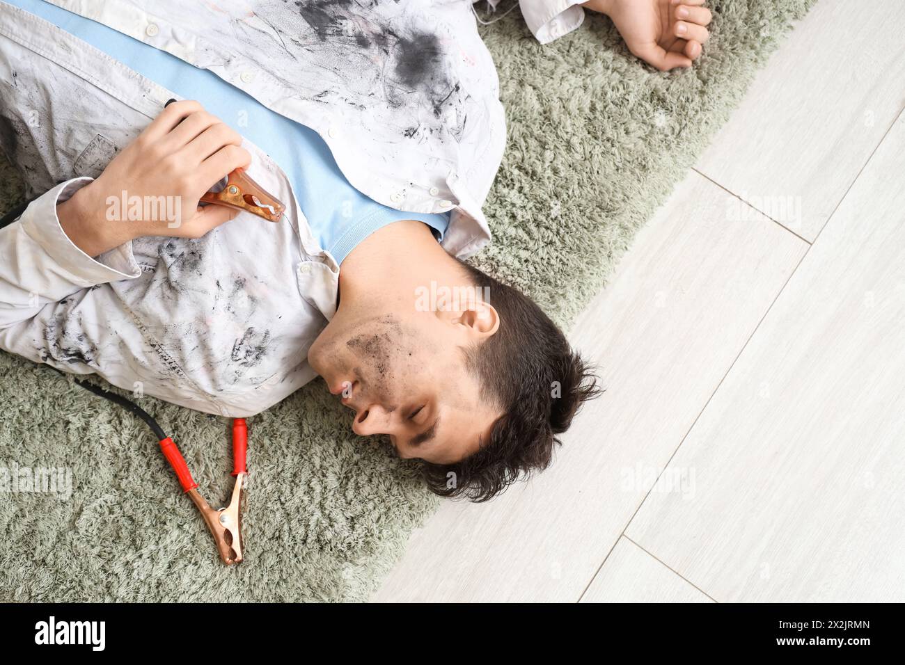 Electrocuted man with burnt face and jumper cables lying on floor at ...