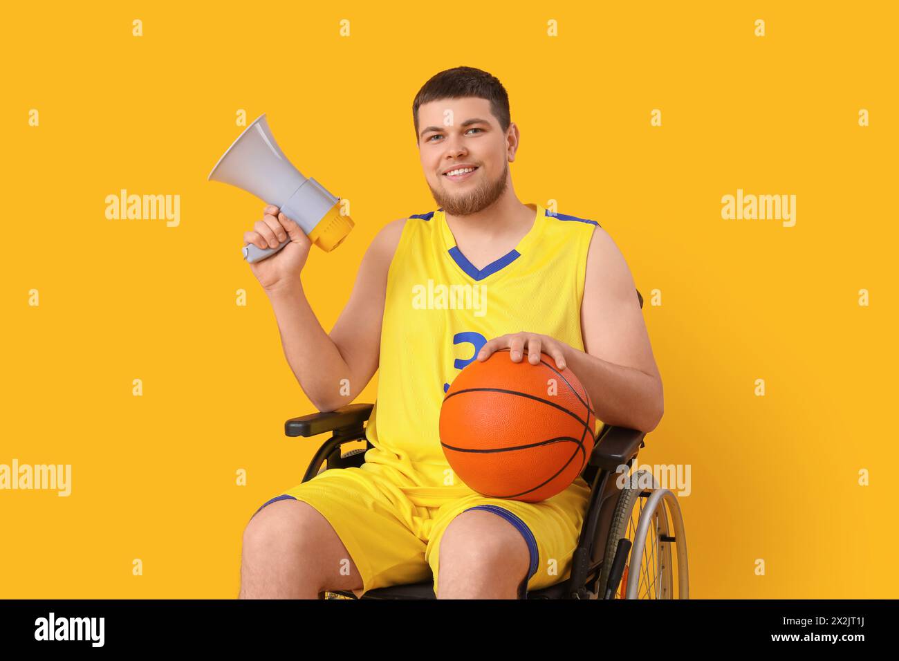 Male basketball player in wheelchair with megaphone on yellow ...