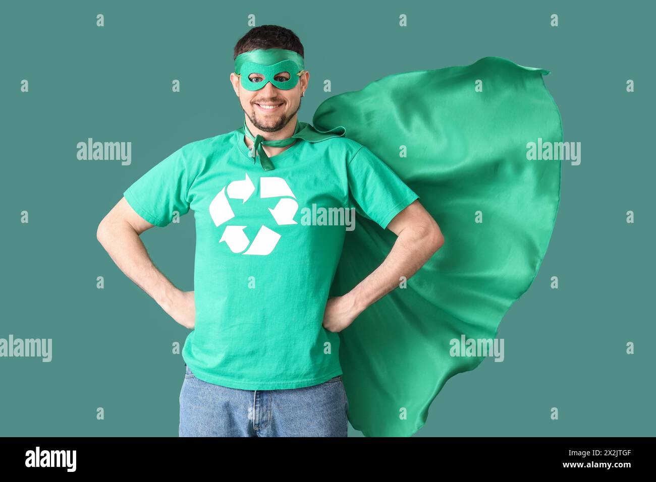 Young man dressed as eco superhero on green background. Ecology concept ...