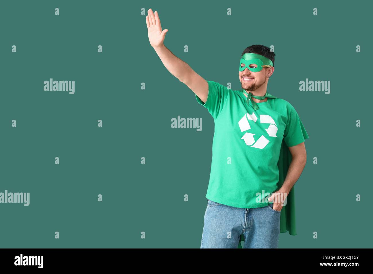Young man dressed as eco superhero waving hand on green background ...