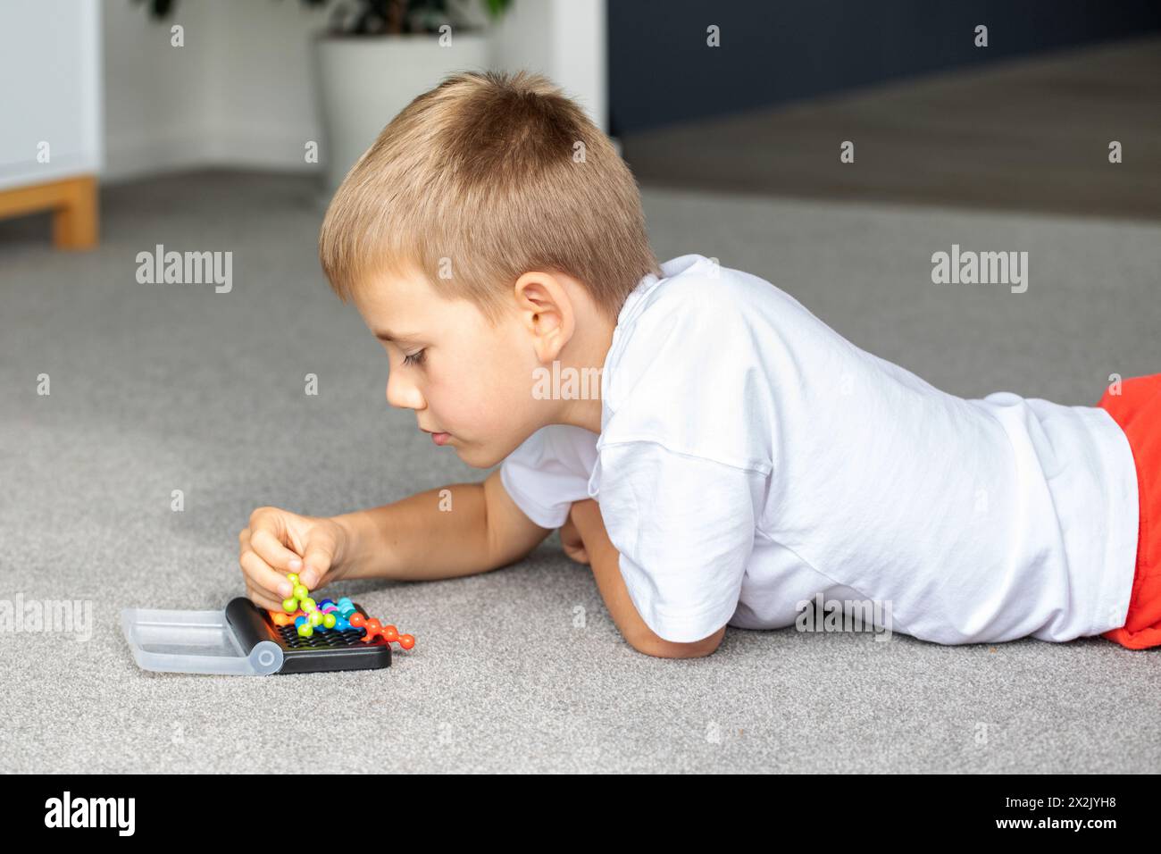 Focused boy deeply engaged in solving a colorful logic puzzle ...