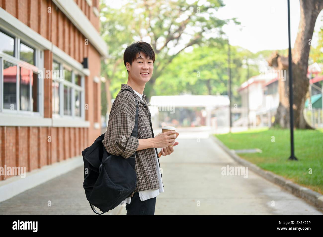 A young Asian man college student with a backpack stands in front of a ...