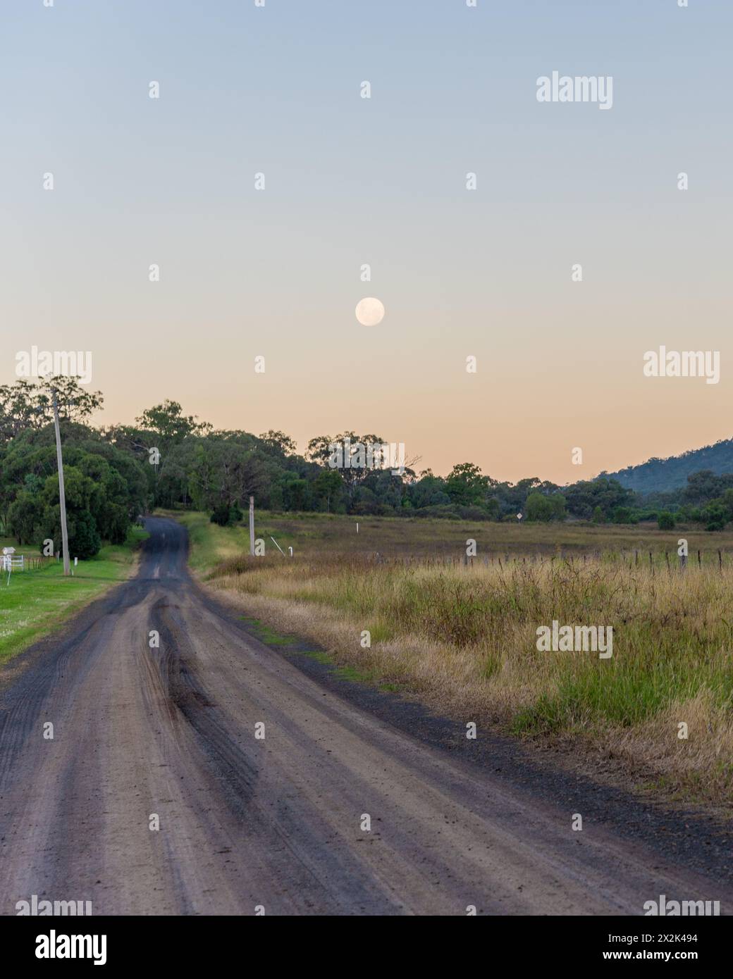 Rural country road in Australia during sunset with full moon rising ...