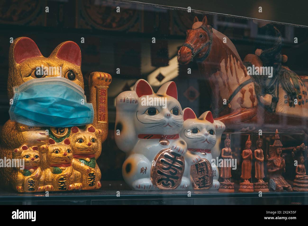 A collection of golden Lucky Cat figurines, one prominently wearing a ...