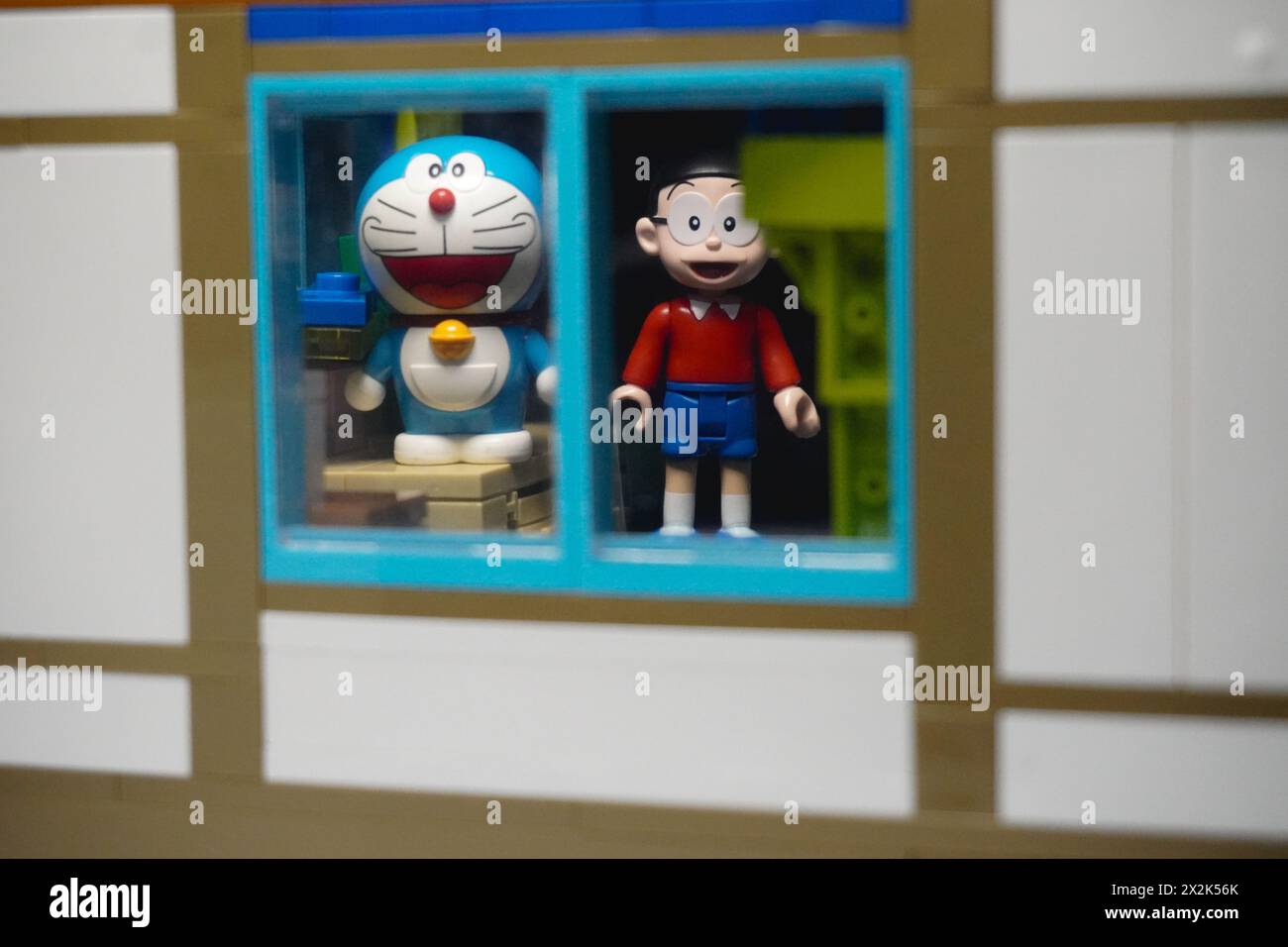 Japanese toy figures (Nobita and Doraemon) standing facing the window ...